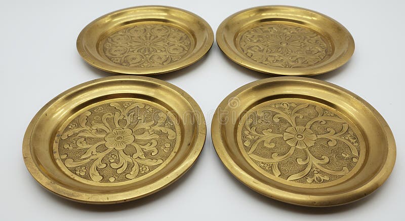 Four Golden Brass Coasters with Intricate Etched Designs on White ...