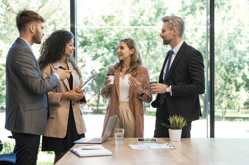 Four Business People Discussing Work Together Using a Tablet in a ...