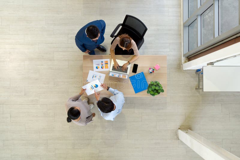 Four Business People Meeting Around a Small Table with Document Papers ...