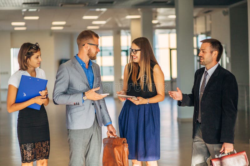 Four Business People Talking and Walking in Office Lobby Stock Image ...
