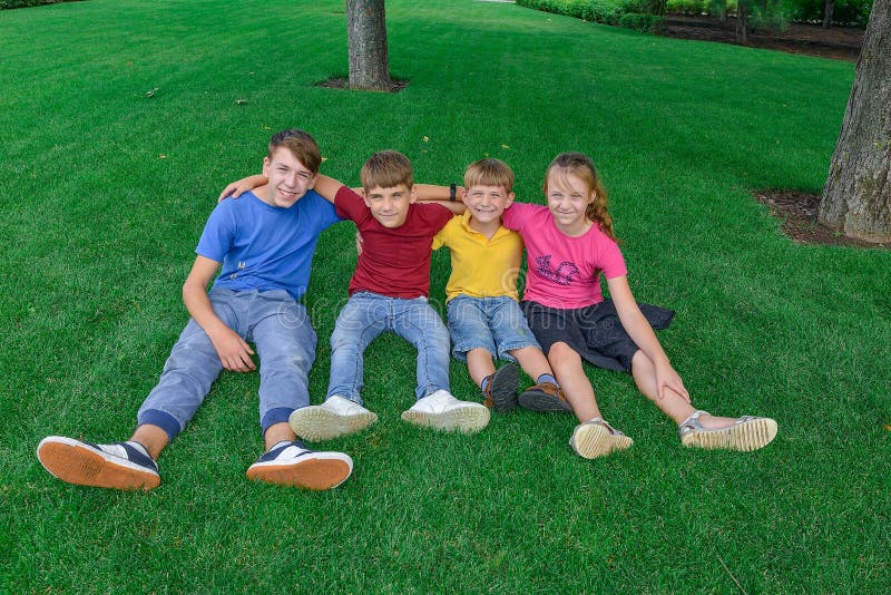 Four Children are Sitting on the Green Grass in the Park Stock Image ...
