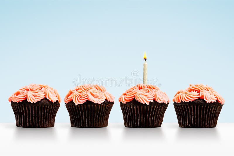 Row of Cupcakes with a Single Lit Candle Isolated on Blue Stock Image ...
