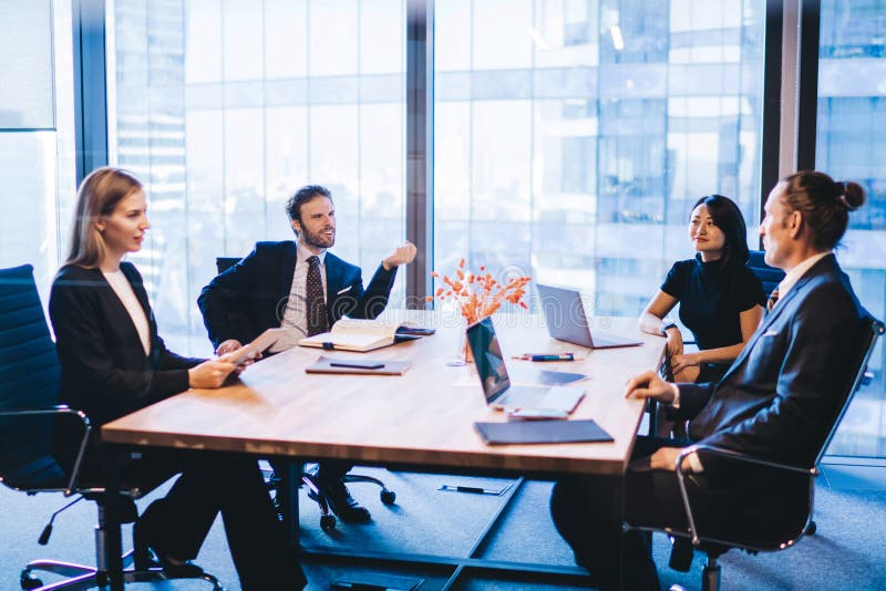 Four Employees Communicating and Discussing Ideas Sitting at Table ...