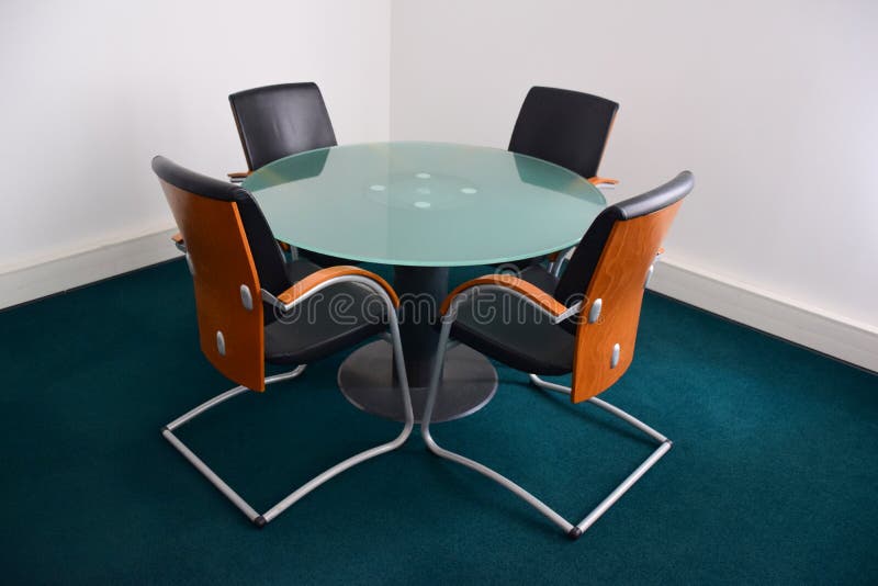 Four Empty Leather Decorative Office Chairs Sit Around a Glass Round ...