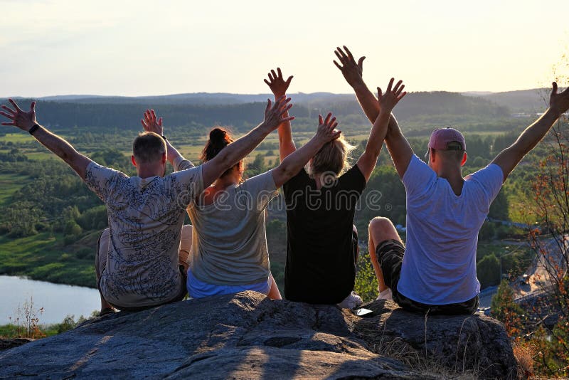 Four Friends Sitting on Edge of Mountain at Sunset Stock Image - Image ...