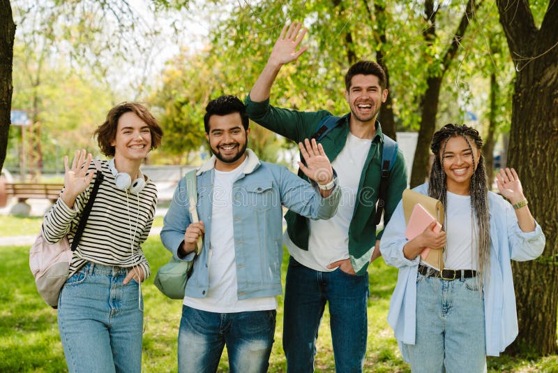 Four Joyful Students Waving Hands while Walking Together in Park Stock ...
