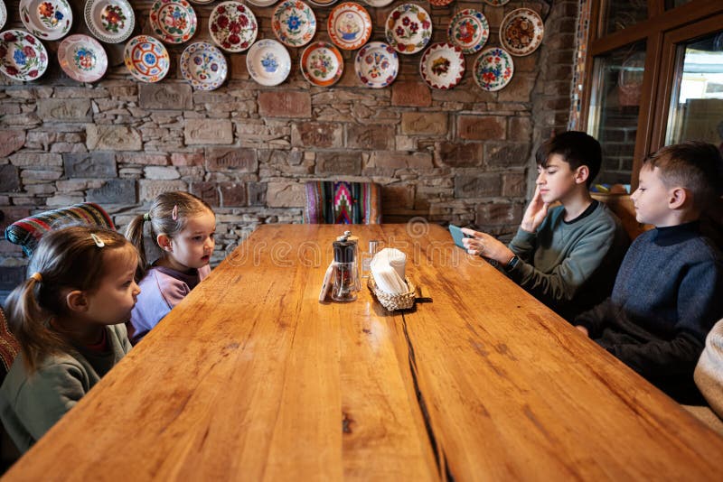 Four Kids Sit in Authentic Ukrainian Restaurant, Looking on Phones ...