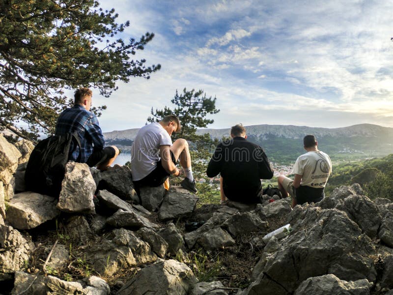 Four Men Seated On Rocks Facing Mountain Picture. Image: 116695709