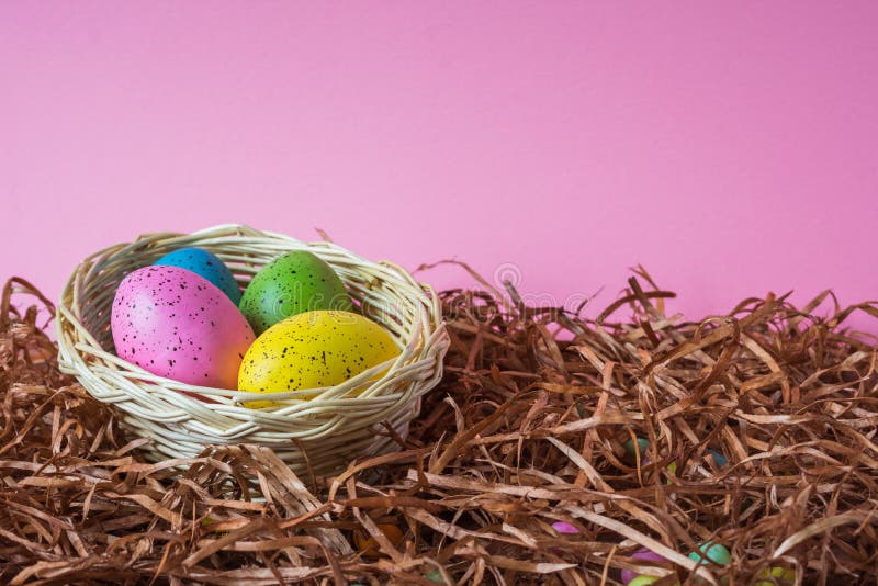 Four Multicolor Easter Eggs in a Basket on Pink Background. Easter ...