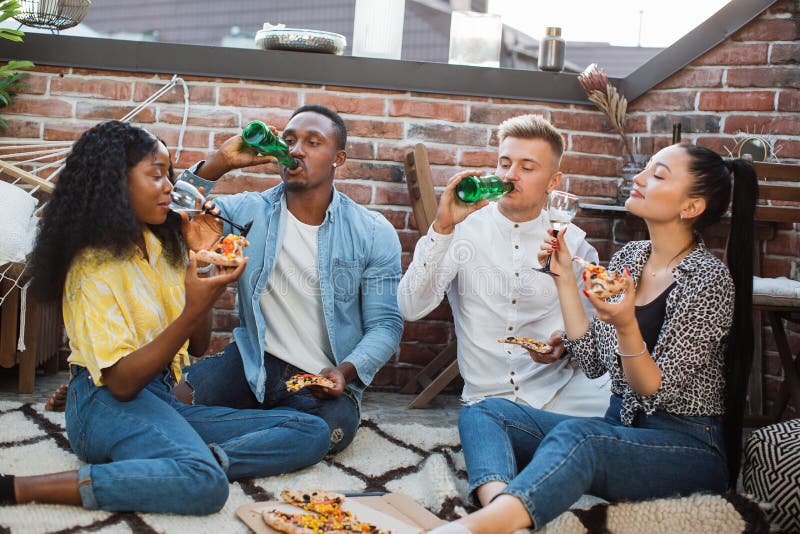 Four Multicultural People Drinking Alcohol and Eating Pizza Stock Photo ...