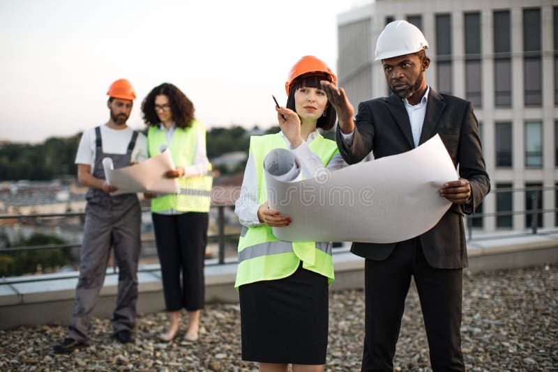 Four Multiethnic Engineers Discussing Construction Process Stock Photo ...