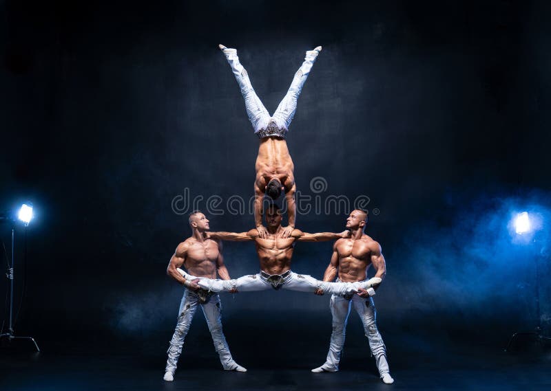 Four Muscular Man Perform Difficult Acrobatic Tricks on Black Studio ...