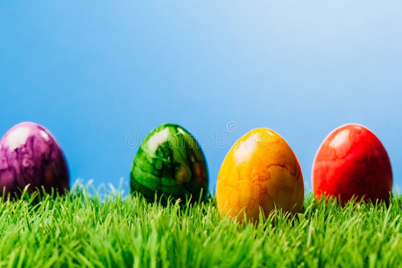 Four Painted Easter Eggs in Grass, Blue Background Stock Image - Image ...
