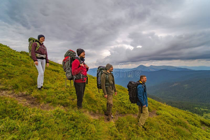 The Four People with Backpacks Standing on the Green Mountain. Stock ...
