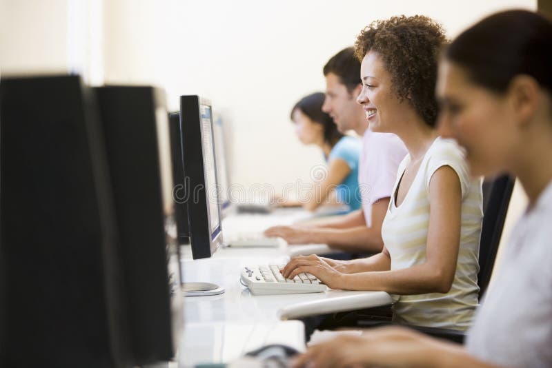 Four People in Computer Room Typing and Smiling Stock Photo - Image of ...