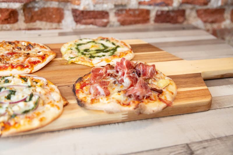 Four Pizzas on a Wooden Board with Focus in a Ham Pizza Stock Image ...