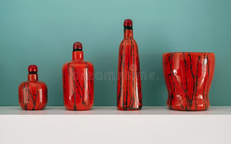 Four Red Murano Glass Items with Black Stripes on a White Shelf Stock ...
