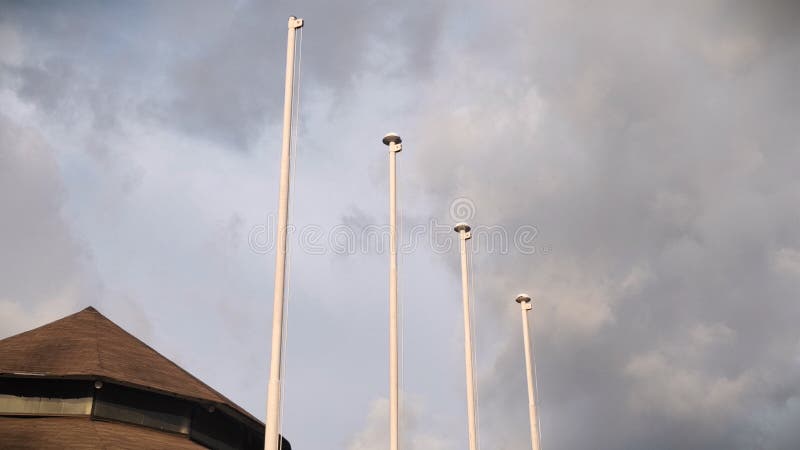 Four Tall Flagpoles Stand Empty Under a Cloudy Sky, Positioned beside a ...
