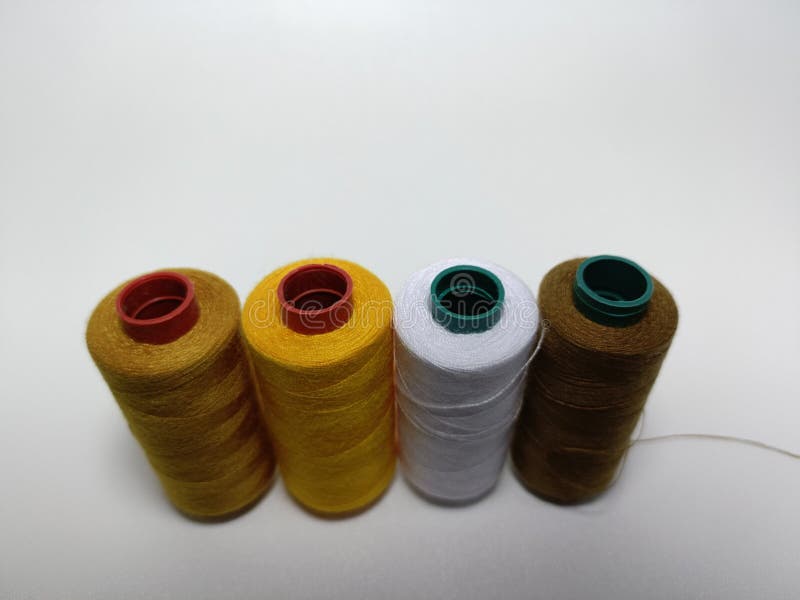 Four Vertical Sewing Thread Spools in Yellow, White, and Brown on White ...