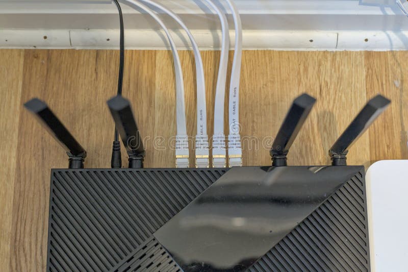 Four White Ethernet Cables Plugged into Black Router with Antennas ...