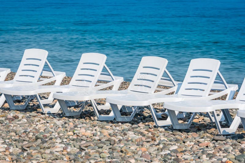 Four White Plastic Beach Chairs on the Beach Stock Photo - Image of ...