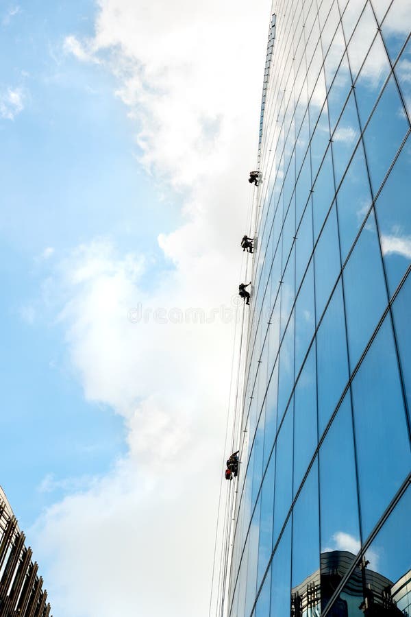 Four Window Washers Work at a Height on a High-rise Building with a ...