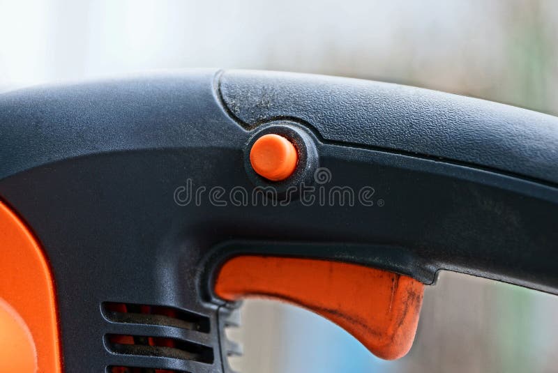 Part of a Power Tool with an Orange Button and a Trigger on a Black ...