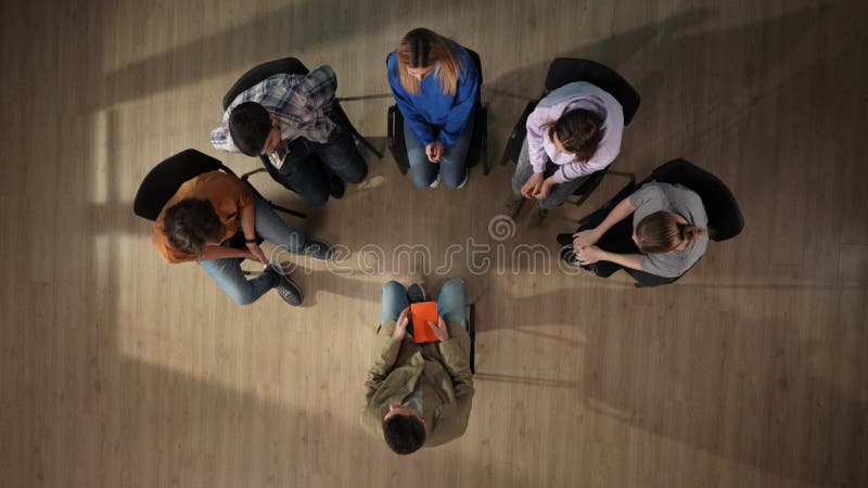 In the Frame Above, a Middle Aged Man Sits Centered with a Notebook in ...