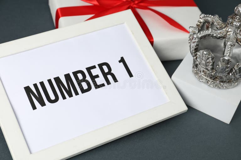 Frame with Phrase Number 1, Crown and Gift Box on Grey Table, Closeup ...