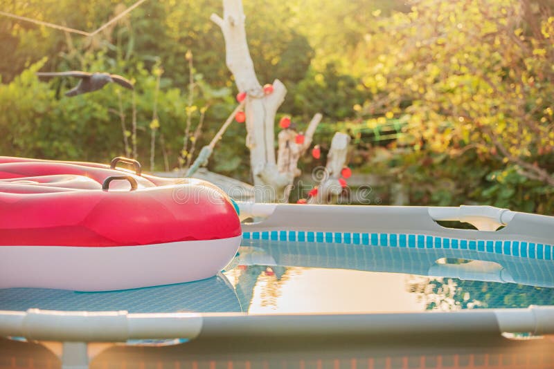 A Frame Pool with Water and an Inflatable Mattress in the Form of a Red ...