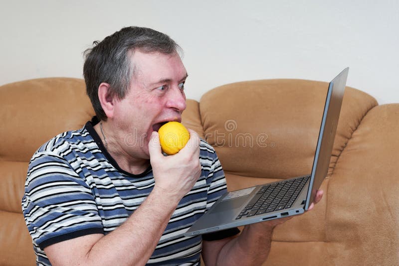 Freak Eats Lemon while Holding a Laptop while Sitting on the Couch ...