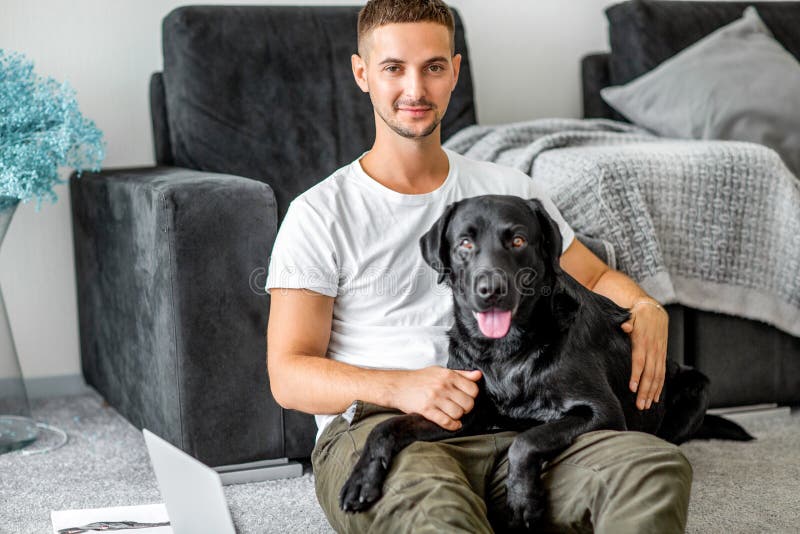 Freelancer Guy Sitting at Home Working with a Dog in an Embrace, Black ...