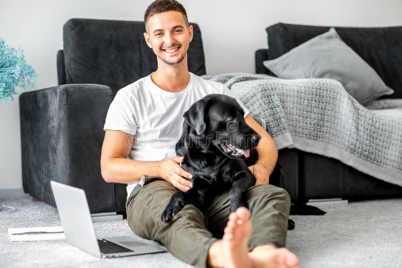 Freelancer Guy Sitting at Home Working with a Dog in an Embrace, Black ...