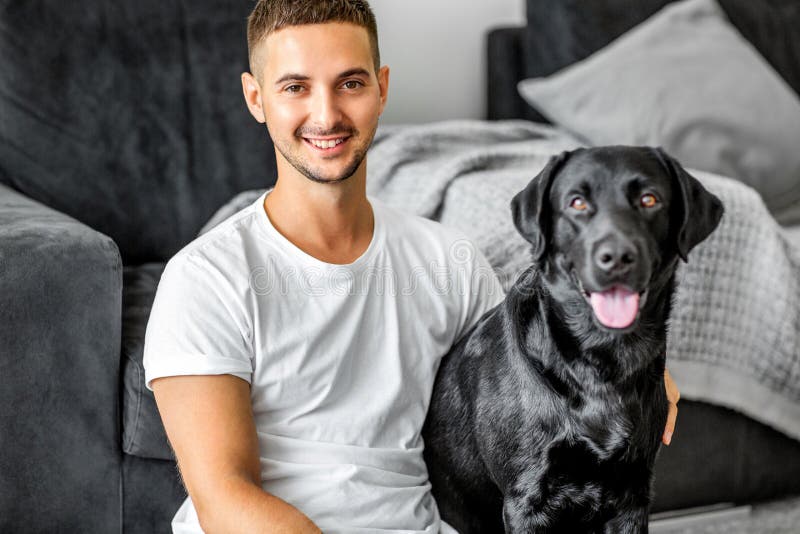 Freelancer Guy Sitting at Home Working with a Dog in an Embrace, Black ...