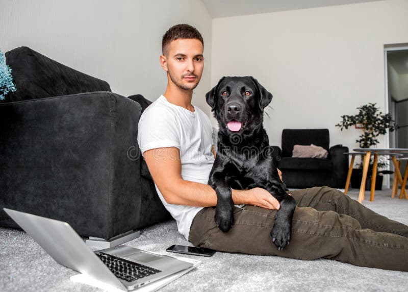 Freelancer Guy Sitting at Home Working with a Dog in an Embrace, Black ...