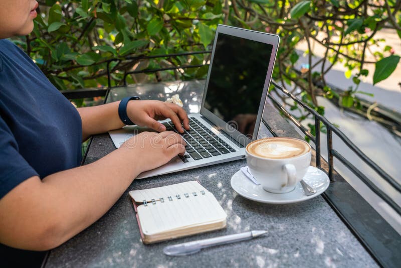 Freelancer Using Laptop Next To Notebook and Cup of Cappuccino Stock ...