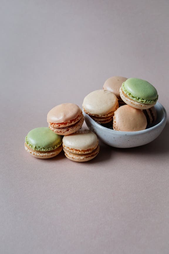French Multicolored Mini Macarons in a Small Bowl on Beige Background ...