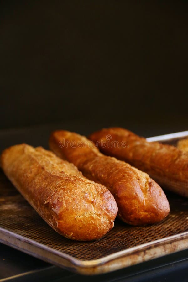 Fresh Baguette Bread on a Baking Sheet and Dark Background Stock Photo ...