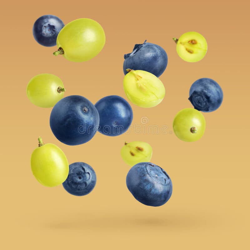 Fresh Blueberries and Grapes Falling on Dusty Gold Background Stock ...