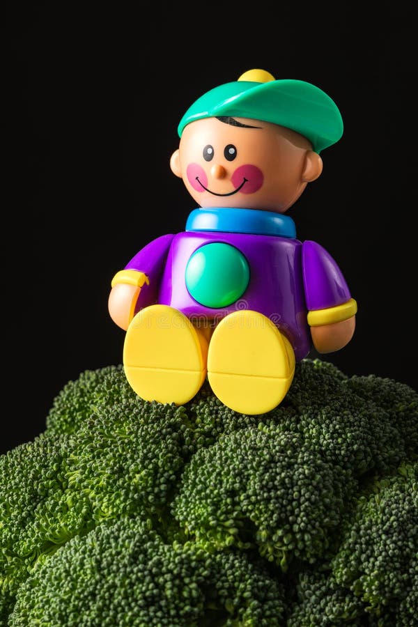 Fresh Broccoli Florets and Plastic Toy Boy on Black Rustic Background ...