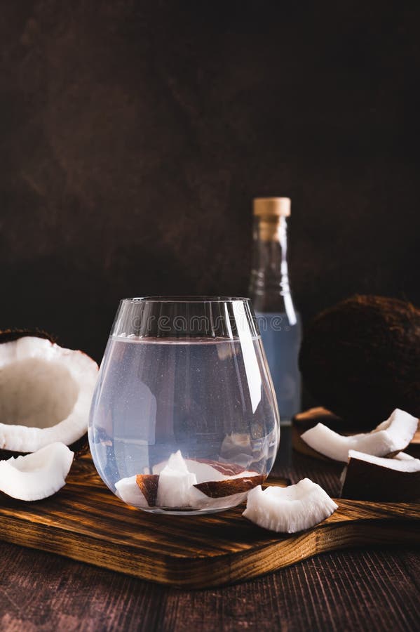 Fresh Coconut Water in a Glass and Coconut Pieces on the Table Vertical ...