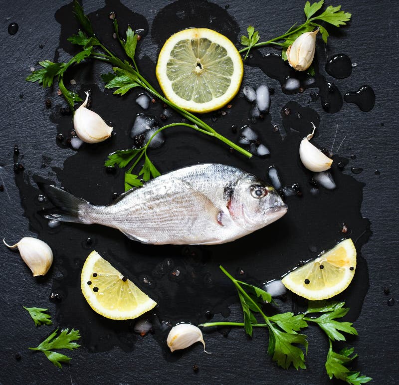 Fresh Fish Orata Over a Black Stone with Vegetables Stock Photo - Image ...