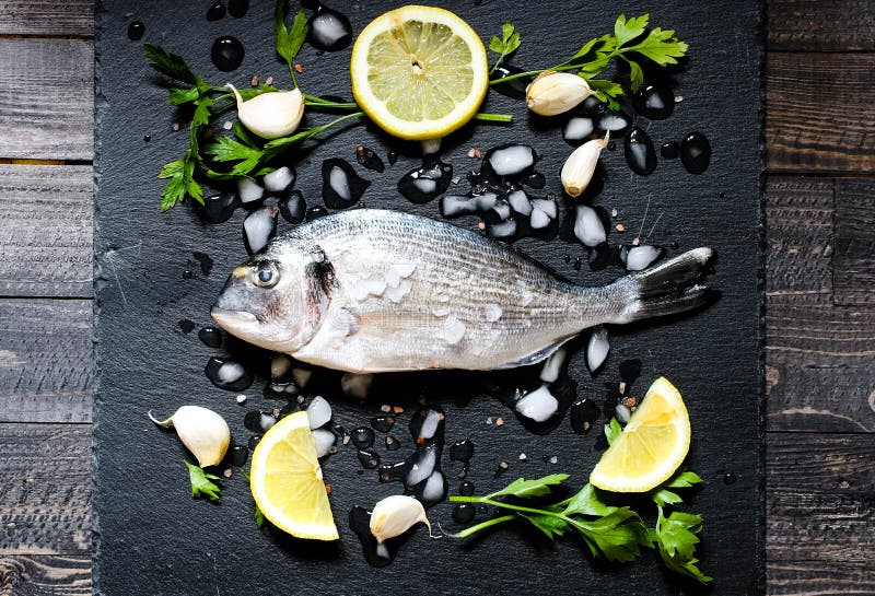 Fresh Fish Orata Over a Black Stone with Vegetables Stock Photo - Image ...