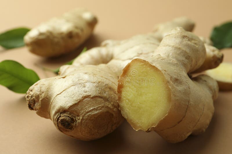 Fresh Ginger and Green Leaves on Light Pale Brown Background, Closeup ...