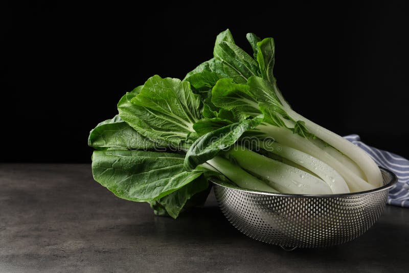 Fresh Green Pak Choy Cabbages with Water Drops in Sieve on Grey Table ...