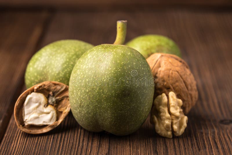 Fresh Harvest of Walnuts on a Wooden Background. Green and Brown Nuts ... Fresh Harvest of Walnuts on a Wooden Background. Green and Brown Nuts ...