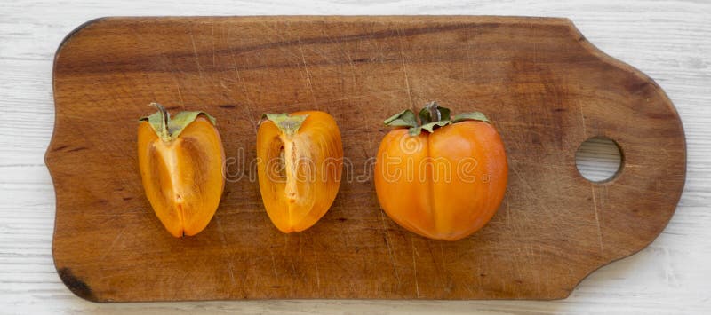 Fresh Persimmon on a Rustic Wooden Board Over White Wooden Surface, Top ...