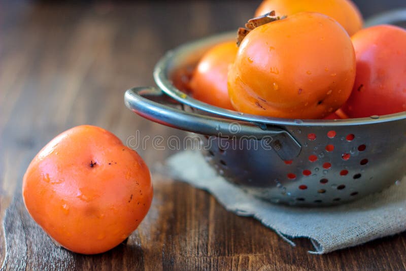 Fresh Persimmon on Wooden Table and Persimmons on Collander. Stock ...