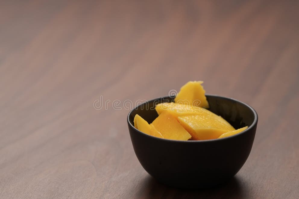 Fresh Sliced Mango in a Ceramic Bowl on Walnut Table Stock Photo ...