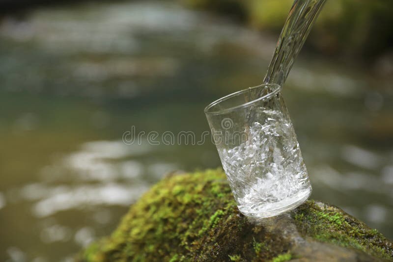 Fresh Water Pouring into Glass on Stone with Moss Near River. Space for ...